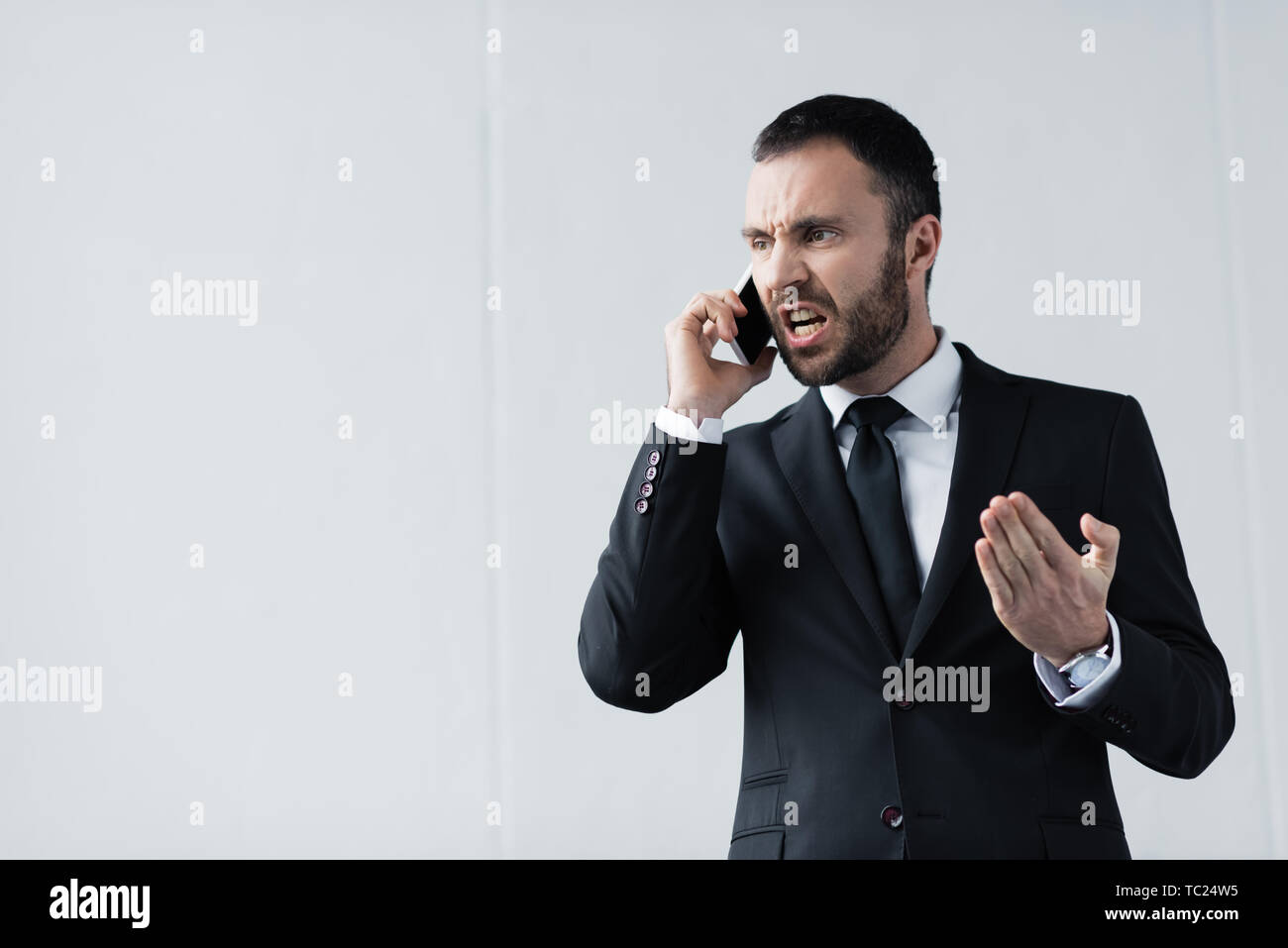 angry businessman in black suit quarreling while talking on smartphone ...
