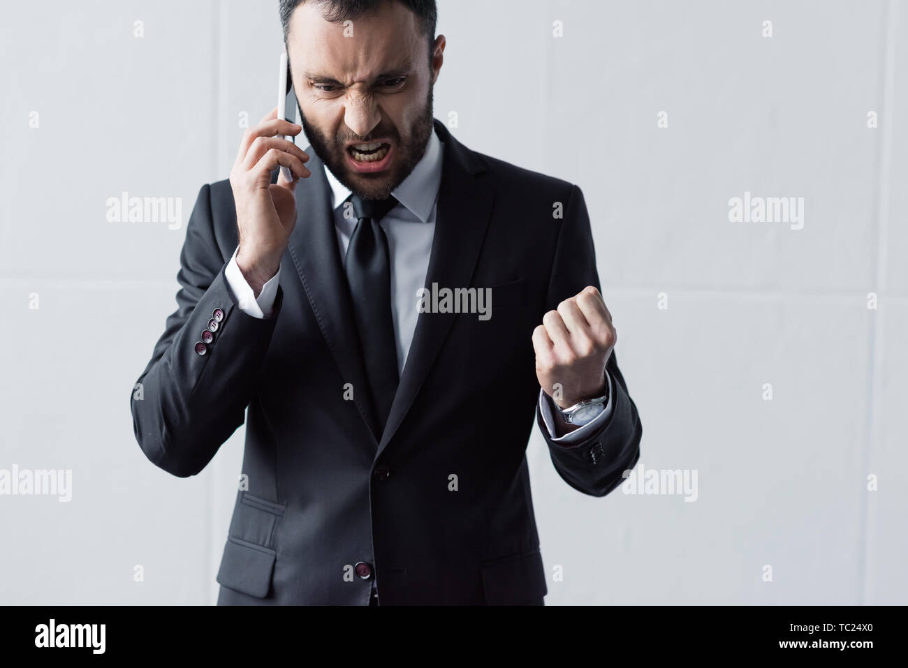 angry businessman in black suit screaming while talking on smartphone ...