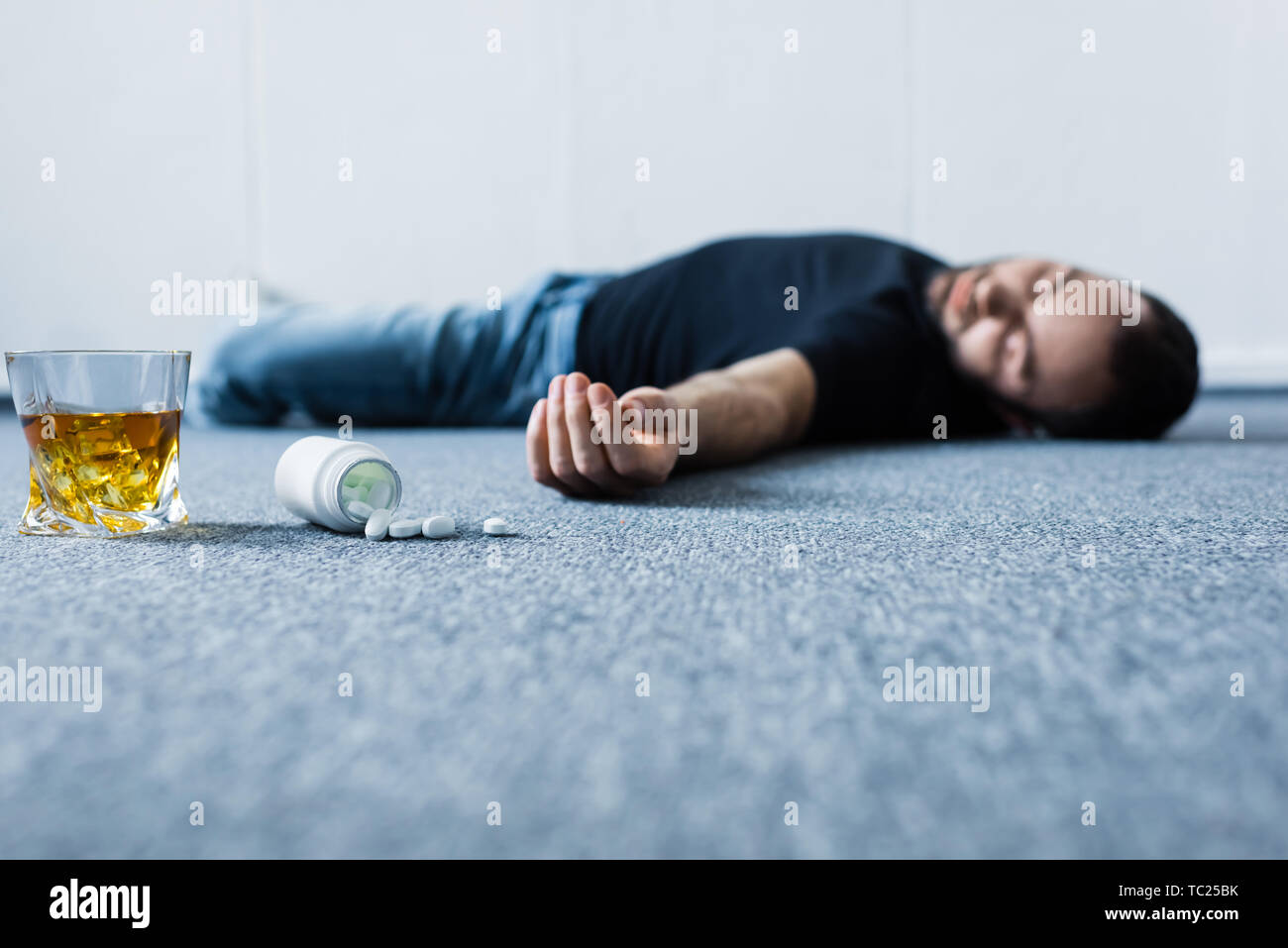 selective focus of adult unconscious man lying on grey floor near ...