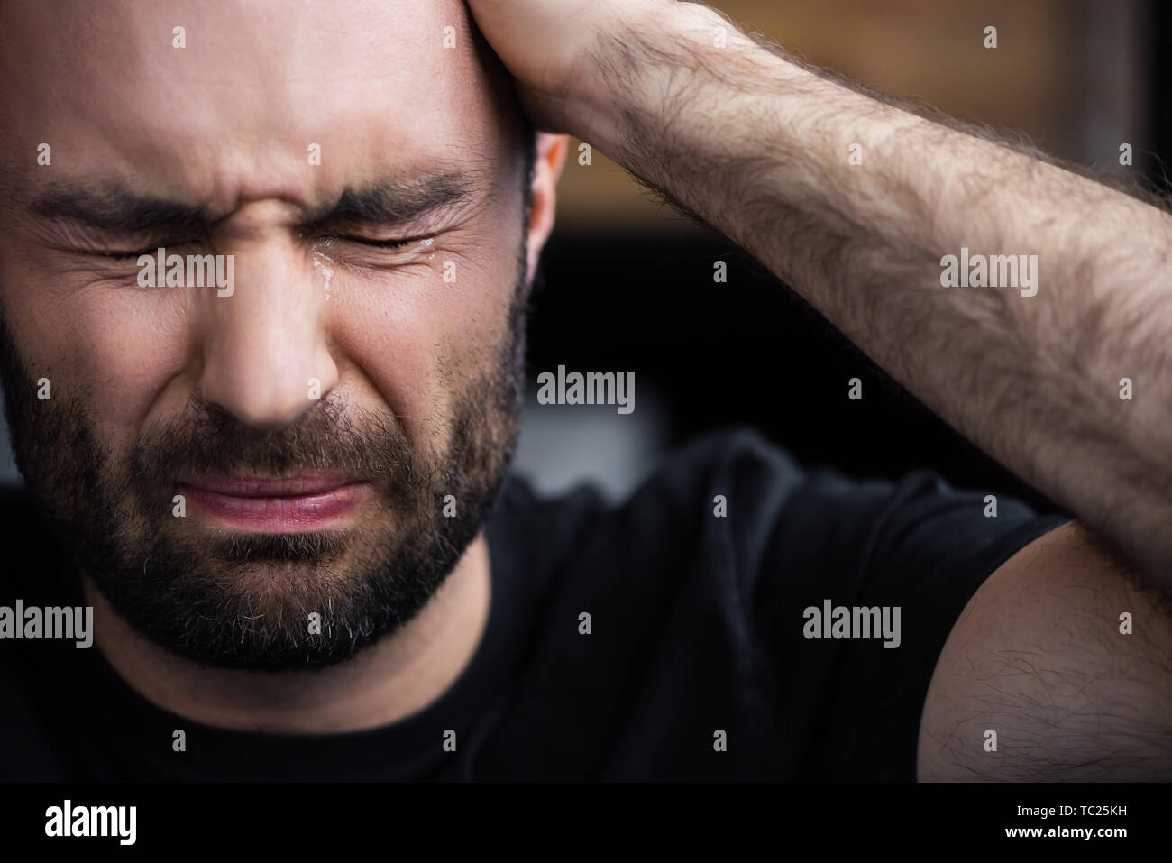 depressed bearded man crying with closed eyes and holding hand on head ...