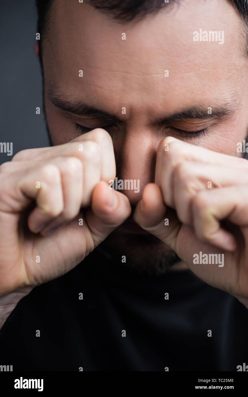 depressed crying man with closed eyes wiping tears away with hands ...
