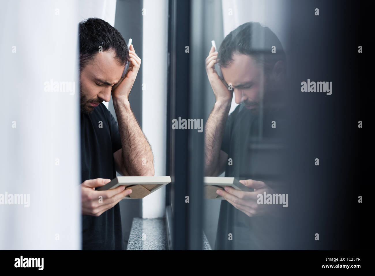 selective focus of crying man holding photo frame while standing by ...