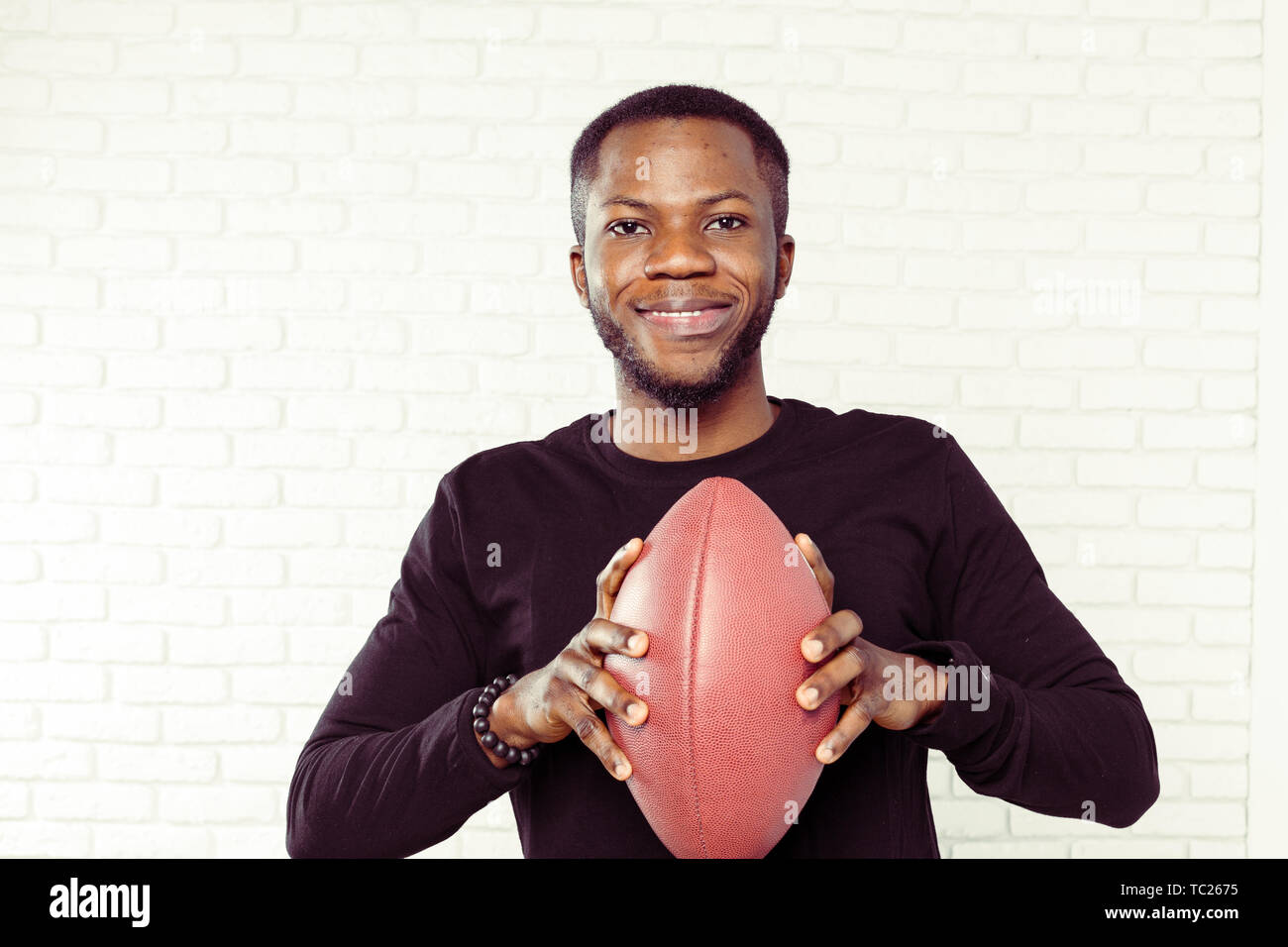 Friendly smiling black man holding a football Stock Photo - Alamy