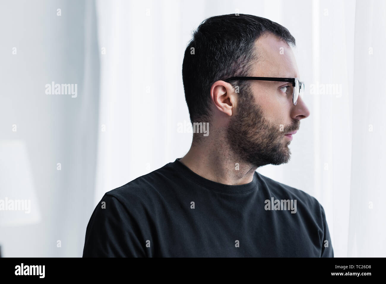 handsome pensive man in glasses looking out window at home Stock Photo ...