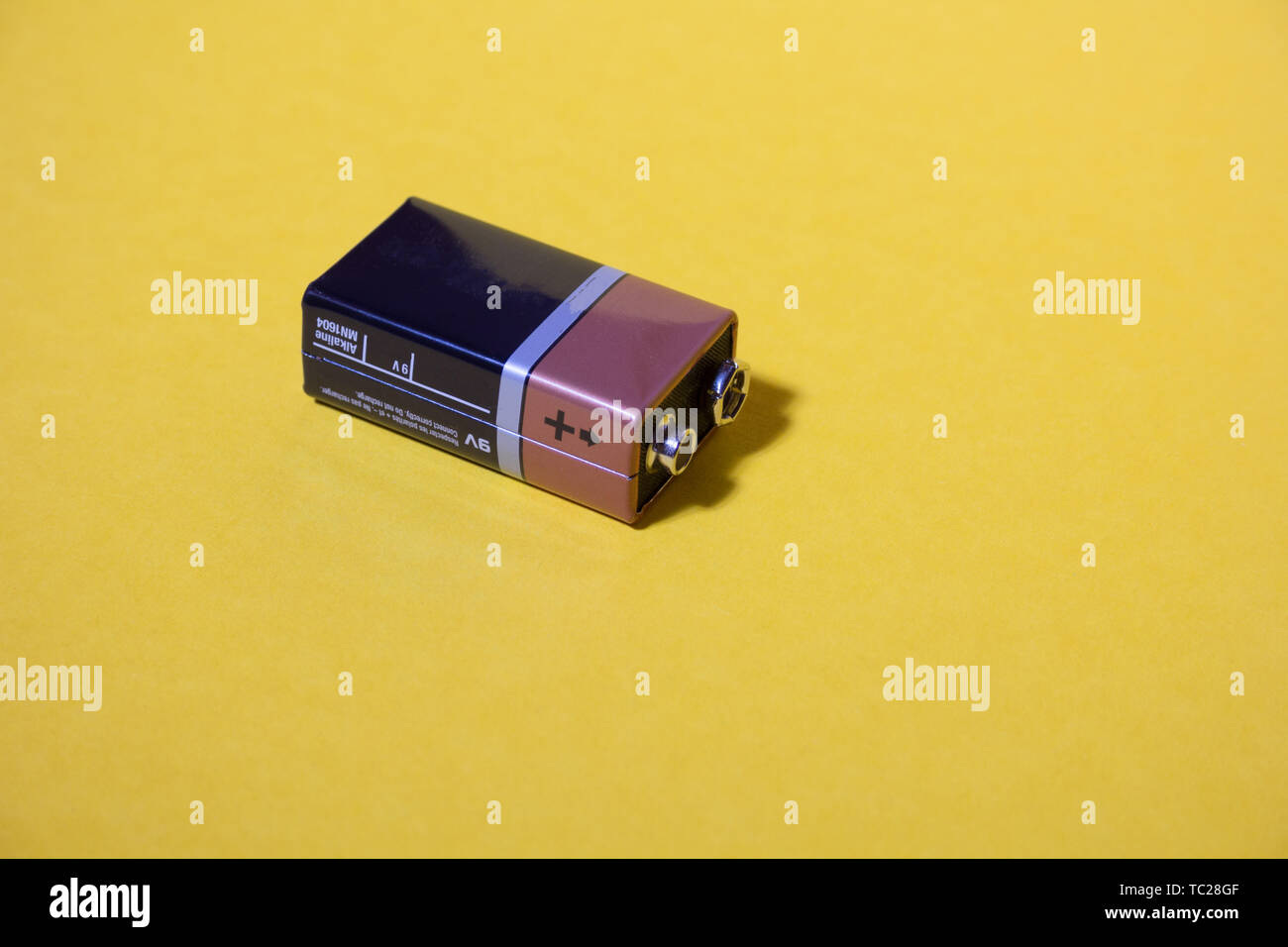 Single alkaline battery on a yellow background Stock Photo - Alamy