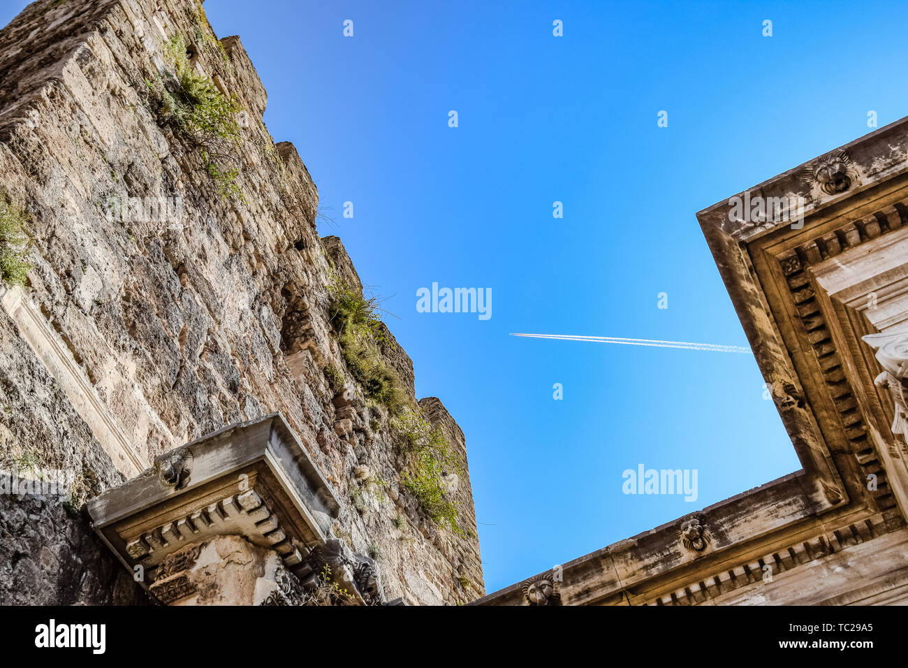 The plane leaving a condensation trail flies high above the gates of ...