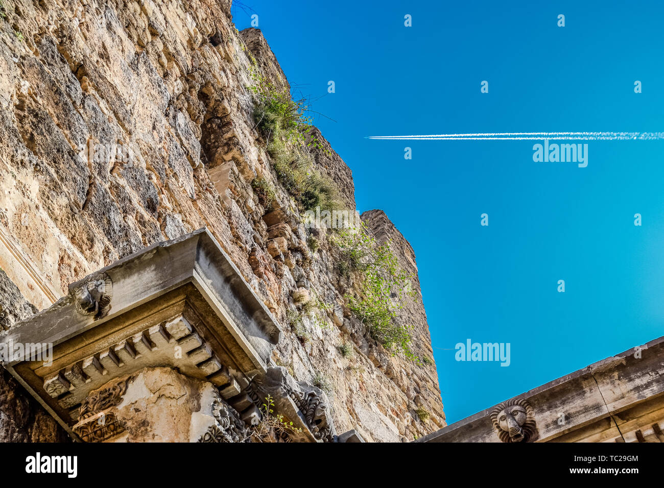 The plane leaving a condensation trail flies high above the gates of ...