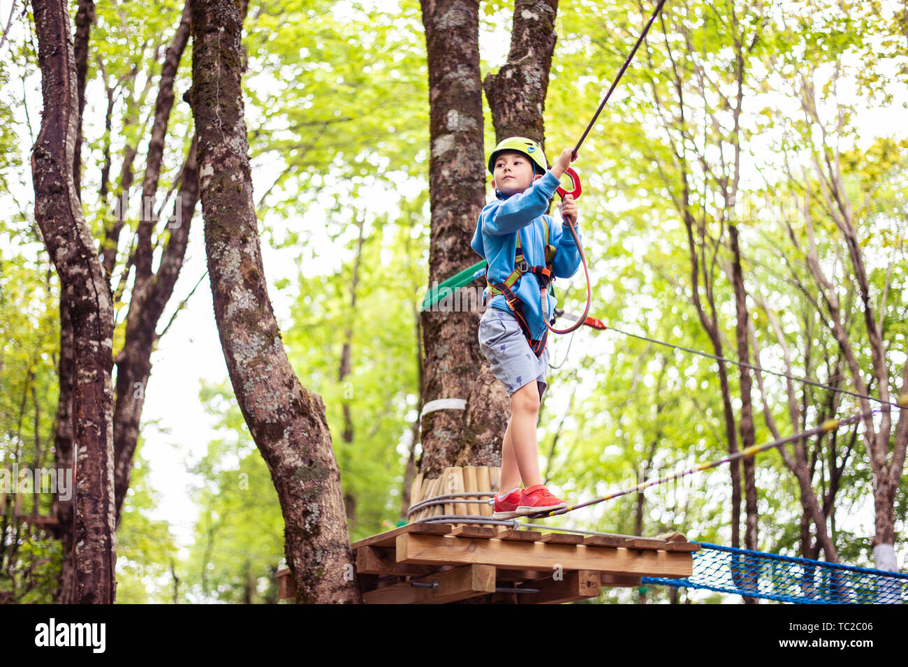 young boy passing cable route among trees, extreme sport in adventure ...