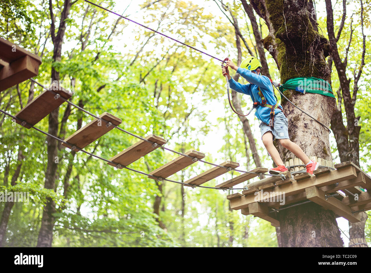 young boy passing cable route among trees, extreme sport in adventure ...