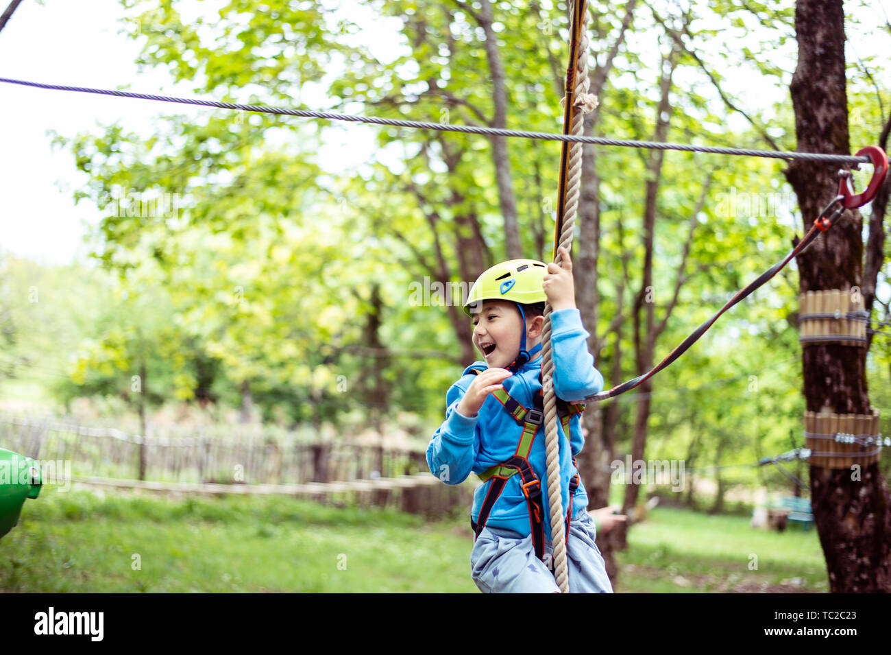 young boy passing cable route among trees, extreme sport in adventure ...