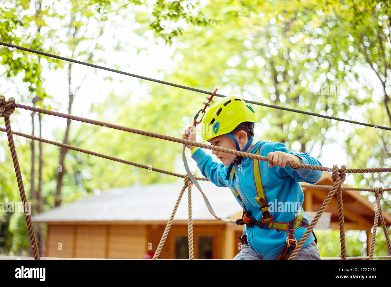 young boy passing cable route among trees, extreme sport in adventure ...