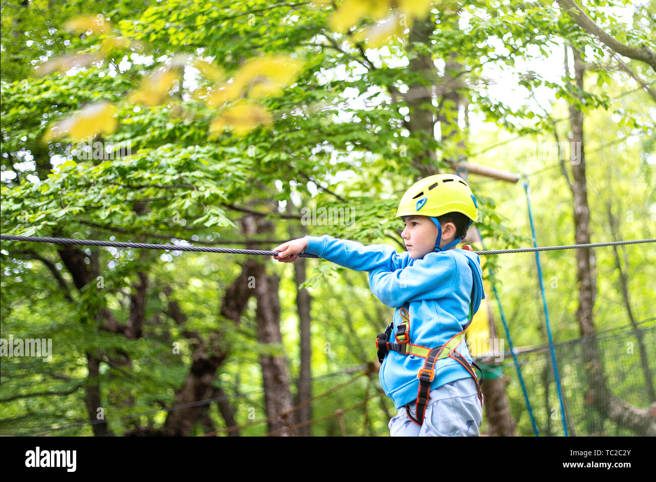 young boy passing cable route among trees, extreme sport in adventure ...