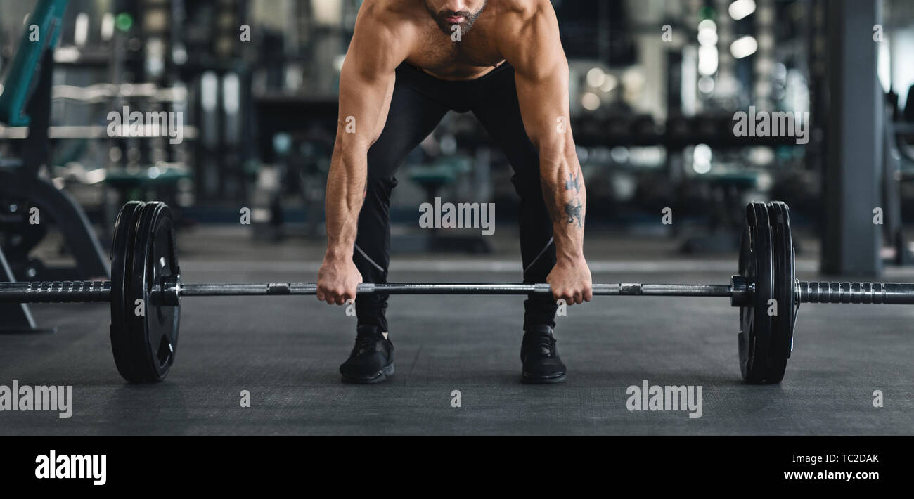 Muscular guy lifting heavy barbell from gym floor Stock Photo - Alamy