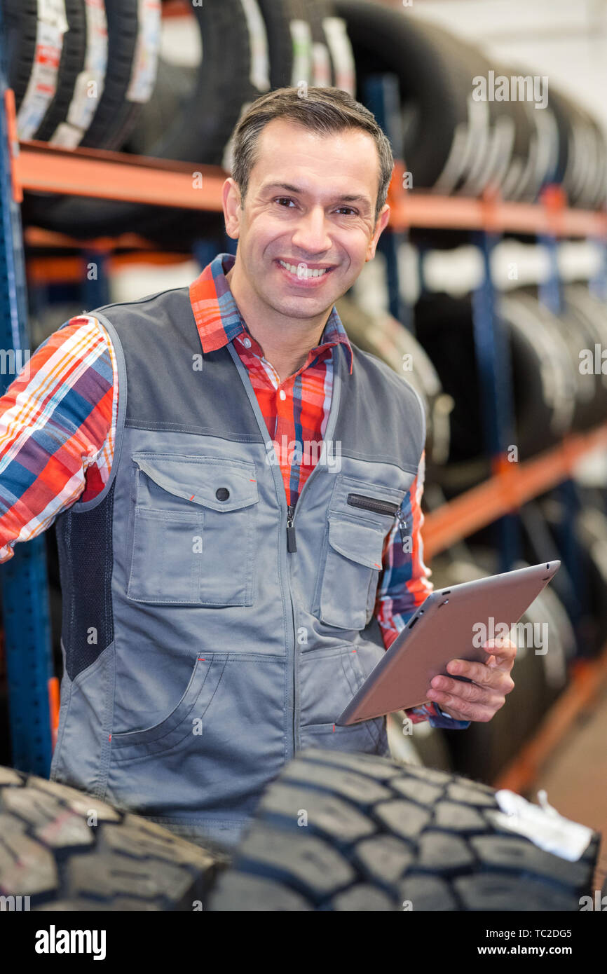 happy mechanic man with car tyres Stock Photo - Alamy