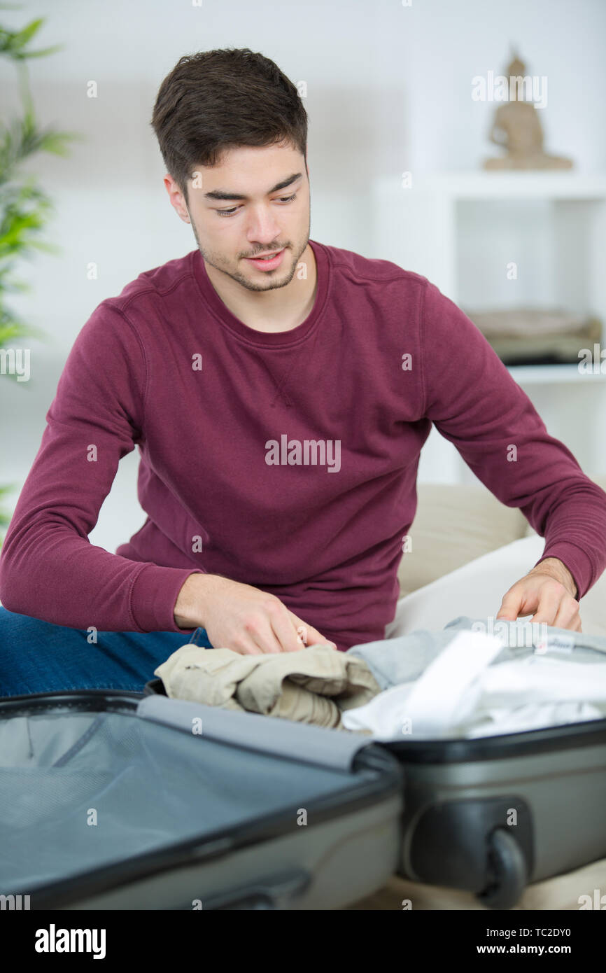 young man packing suitcase Stock Photo - Alamy
