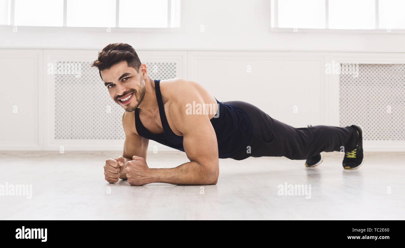 Handsome sporty guy doing plank and smiling Stock Photo - Alamy