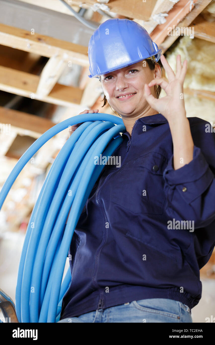 female builder carring pipe making the okay hand gesture Stock Photo ...