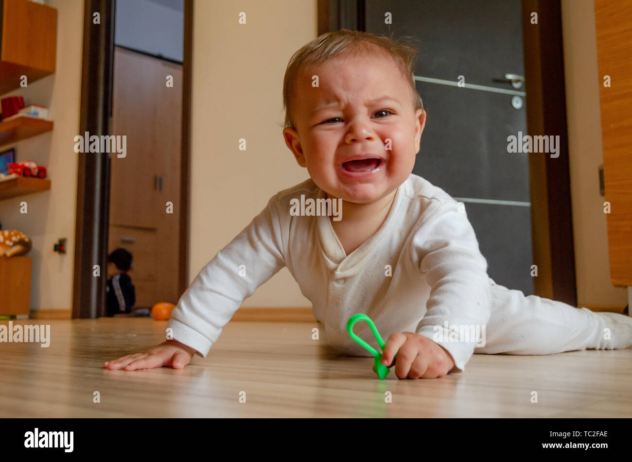 cute six months old baby boy having tummy time on the floor and crying ...