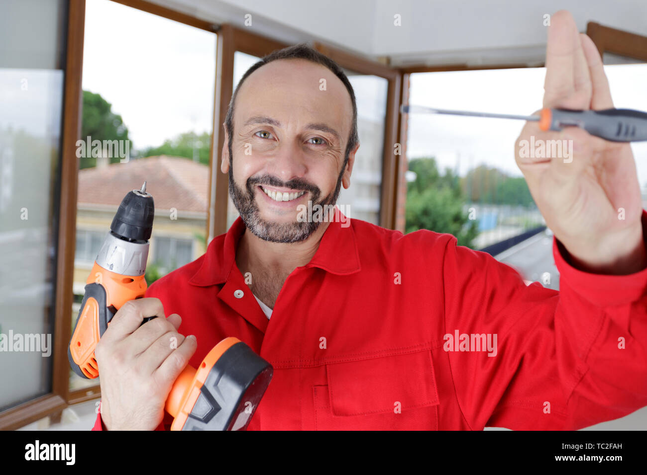 happy man holding a drill and a screwdriver Stock Photo - Alamy