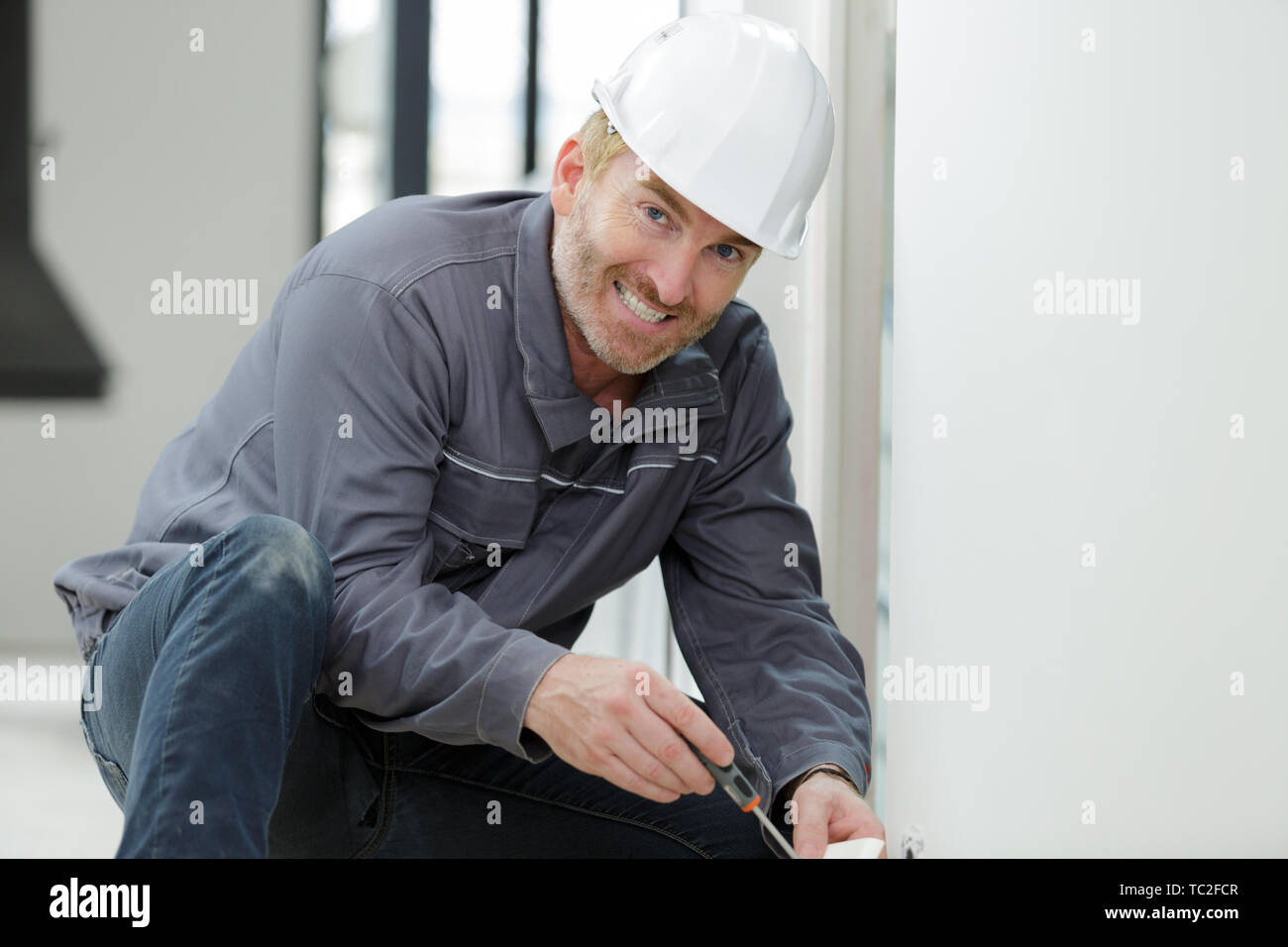 electrician smiling while installing plugs Stock Photo - Alamy