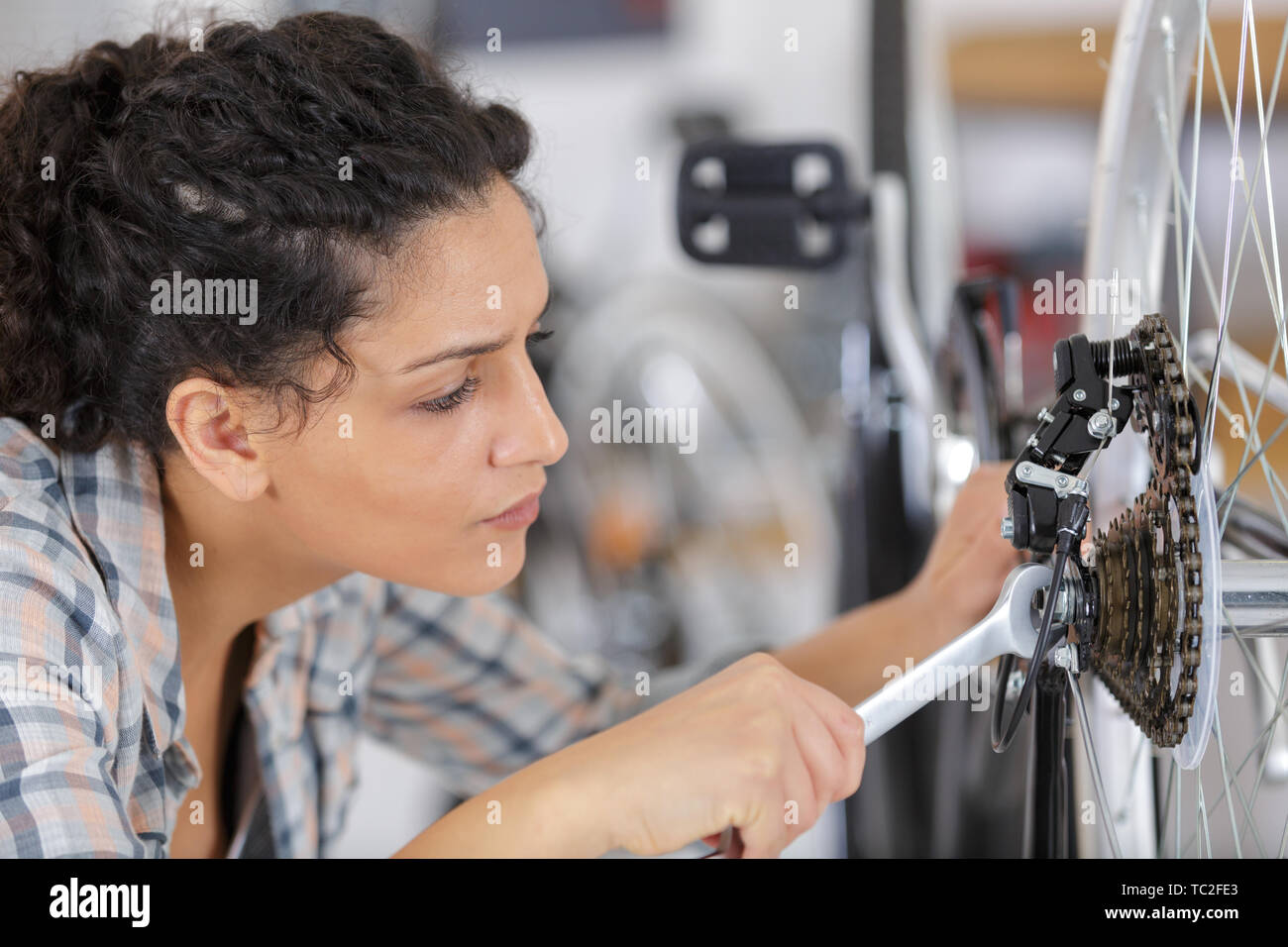 beautiful woman tightening bicycle wheel screws in the garage Stock ...