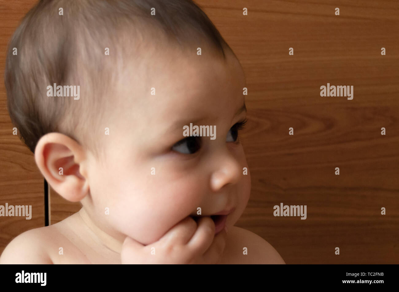 portrait face expresion of cute six months old baby boy putting finger ...