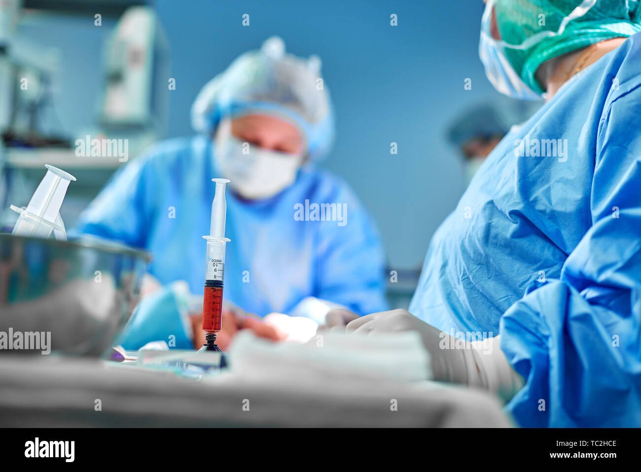 Hands hold a syringe and carry fat with the help of a tool to transfer ...