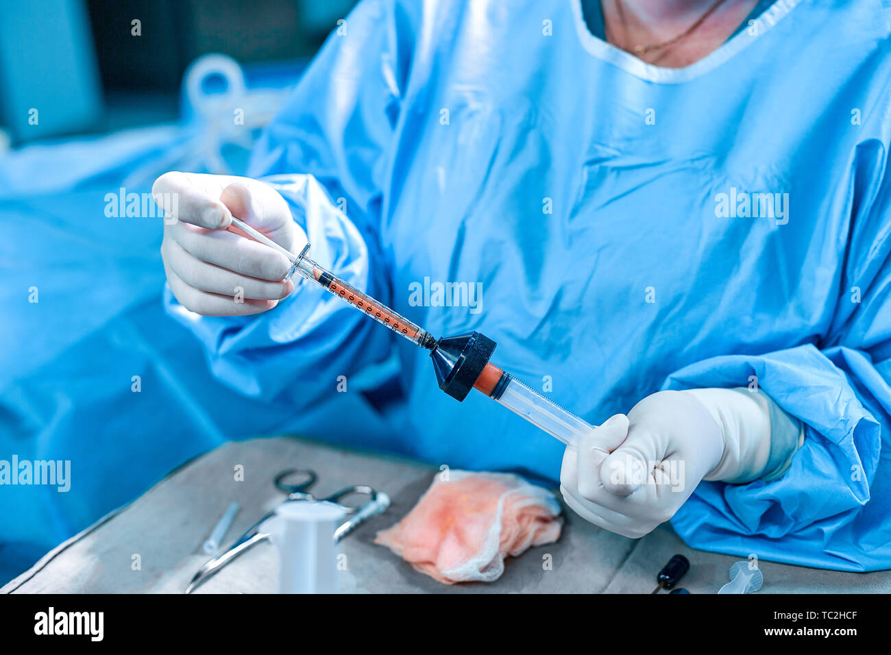 Hands hold a syringe and carry fat with the help of a tool to transfer ...