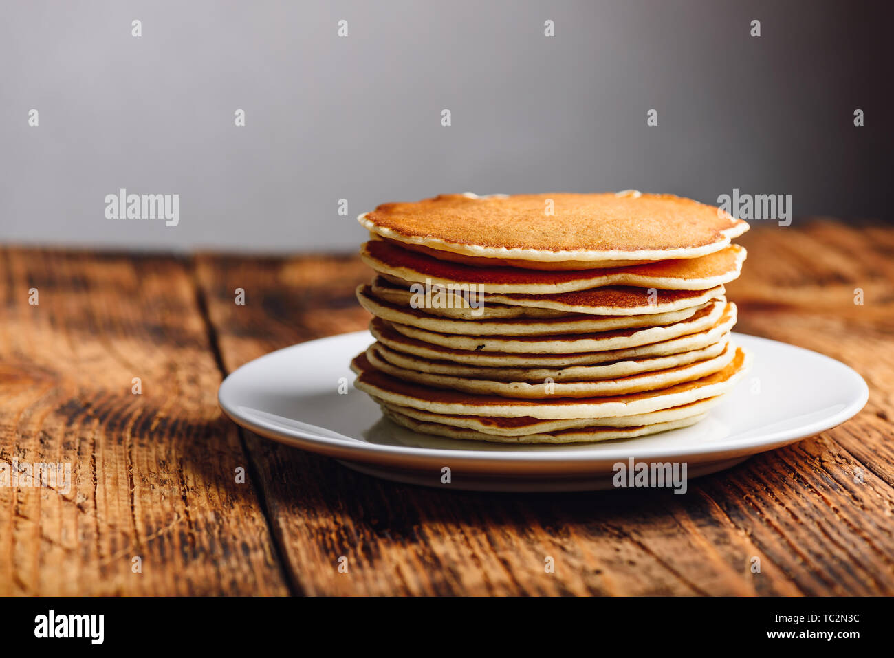 Stack of american pancakes on white plate over wooden table Stock Photo ...