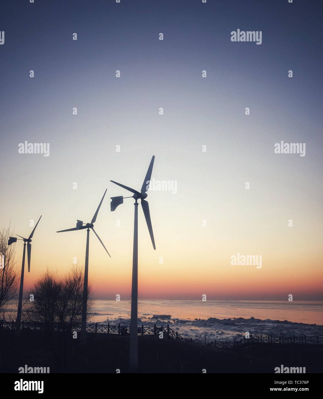 A few windmills stand by the sea, the surrounding cities are powered by ...