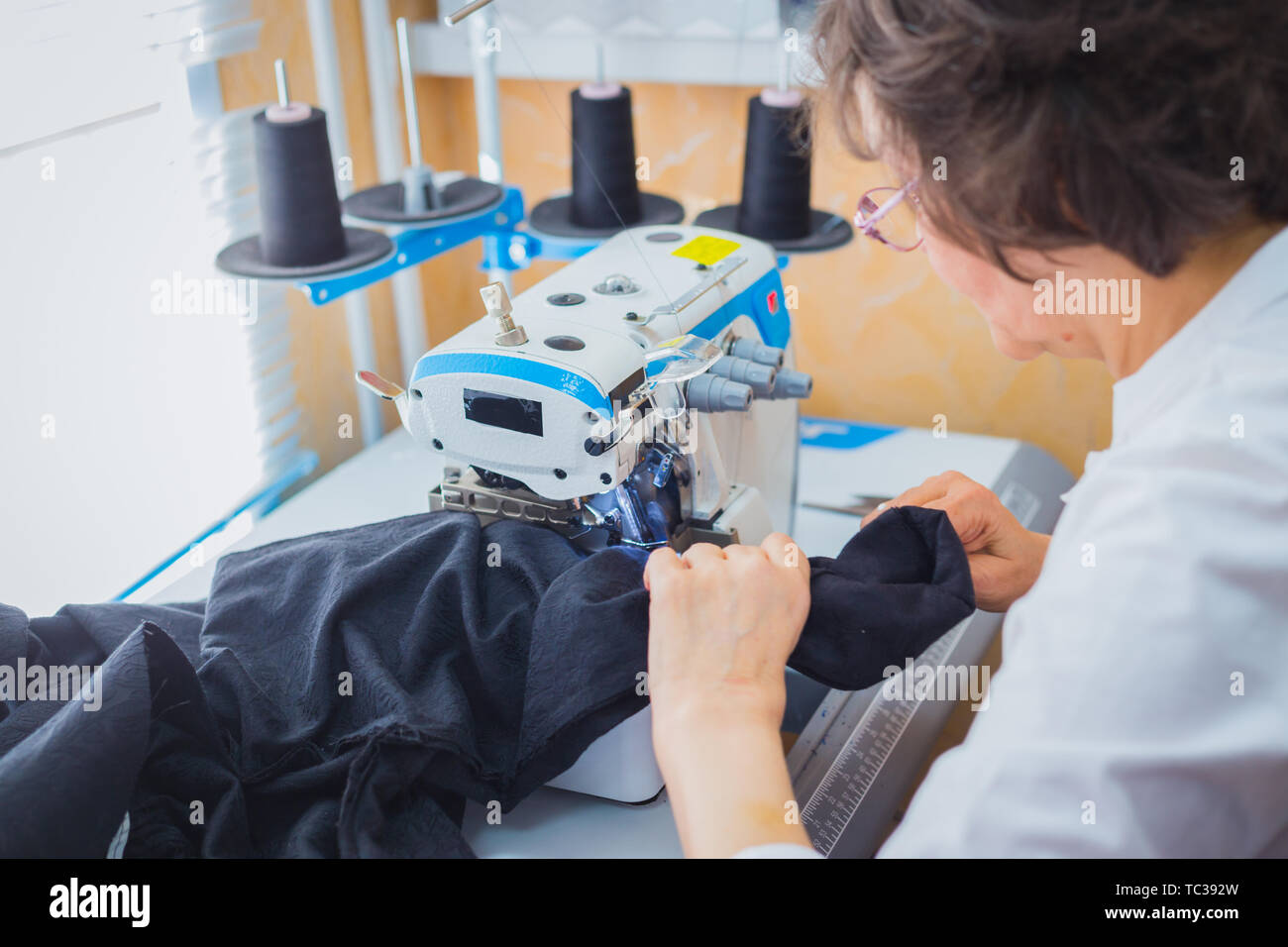 Professional tailor sewing clothes with sewing machine at atelier Stock ...