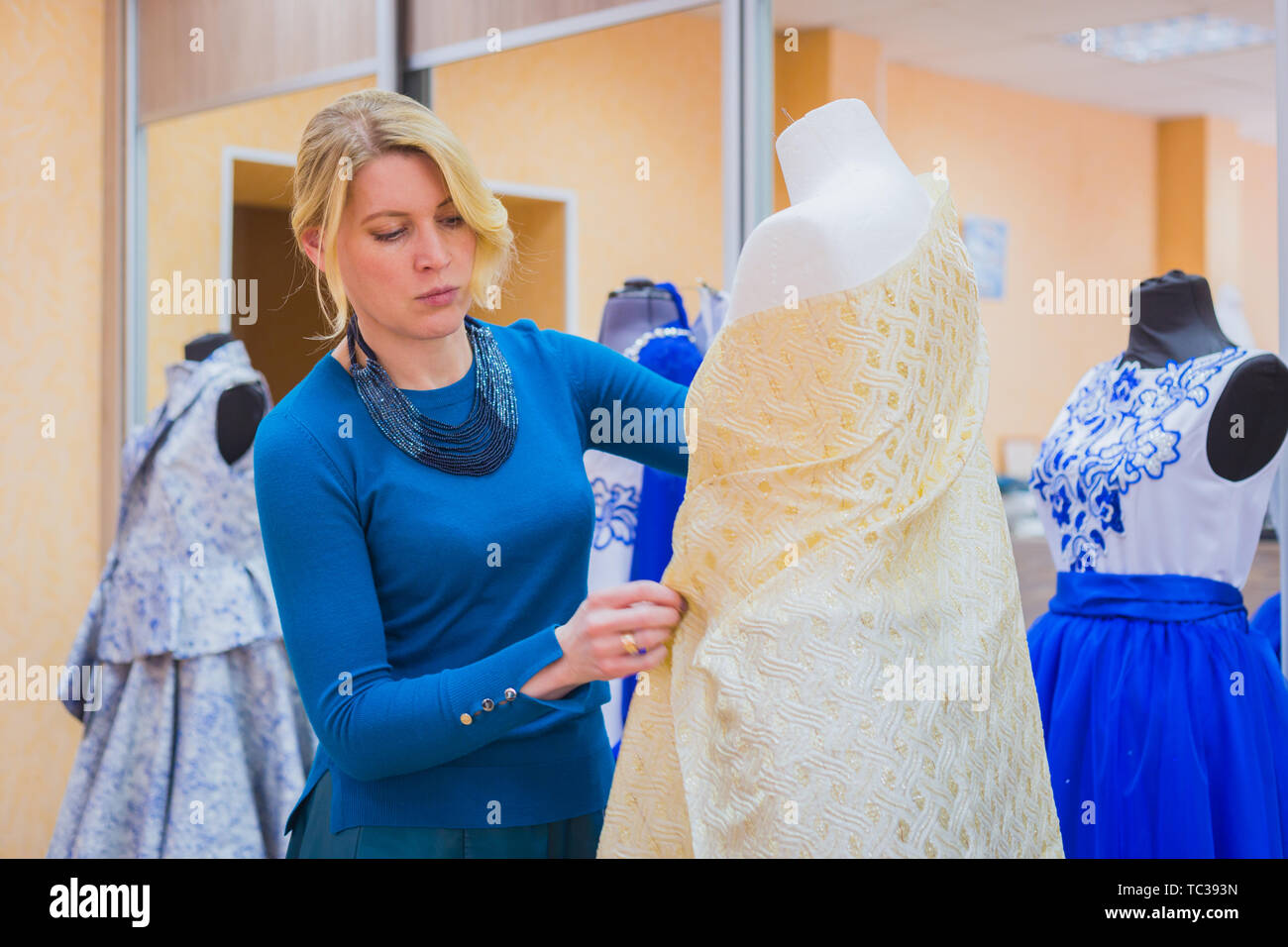 Fashion designer working with new model tailoring dress on mannequin ...