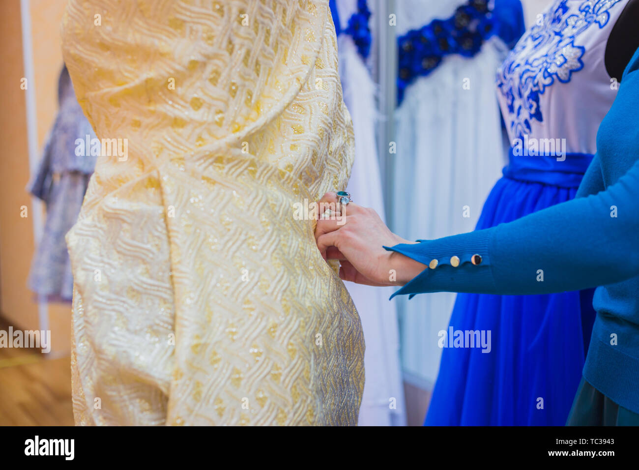 Fashion designer working with new model tailoring dress on mannequin ...
