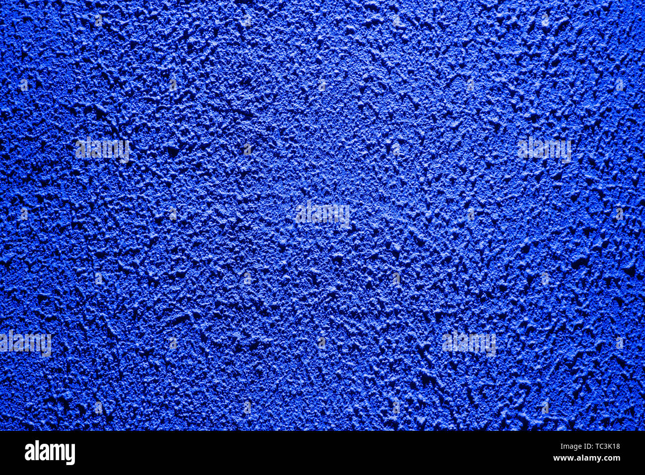 Brightly lit surface covered with bright blue plaster. Trend color ...