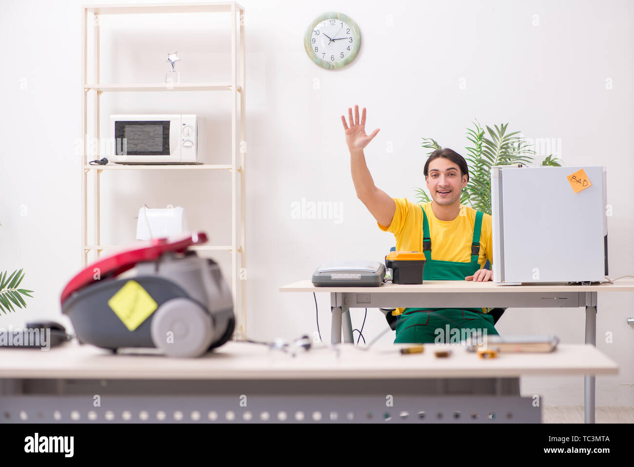 Man repairman repairing vacuum cleaner and fridge Stock Photo - Alamy