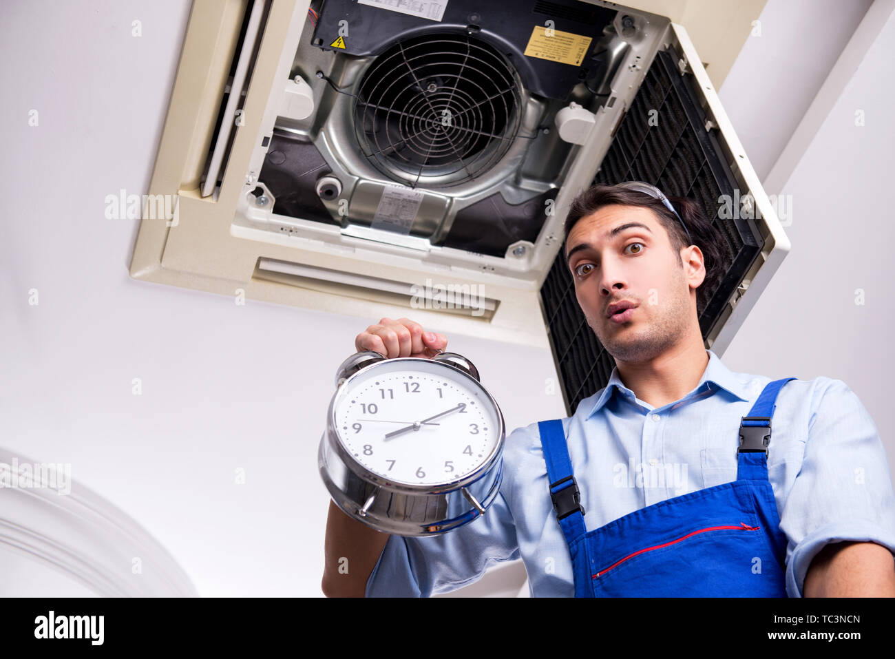 Young repairman repairing ceiling air conditioning unit Stock Photo - Alamy