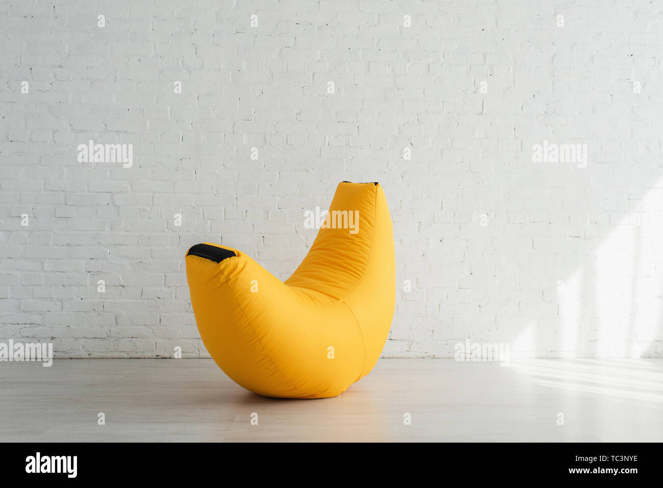 yellow bean bag chair near white brick wall in modern home Stock Photo ...