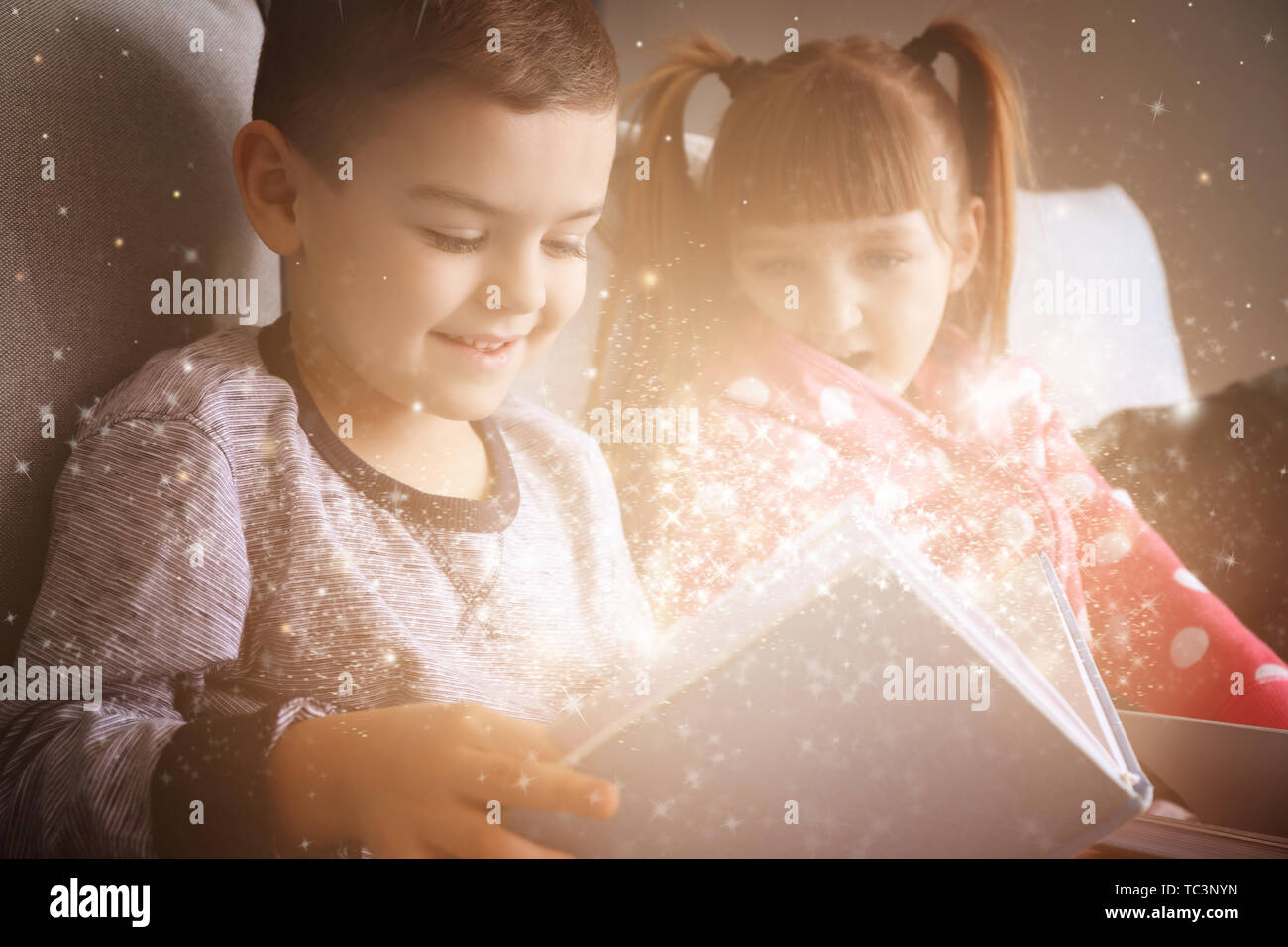 Cute little children reading magic book at home Stock Photo - Alamy