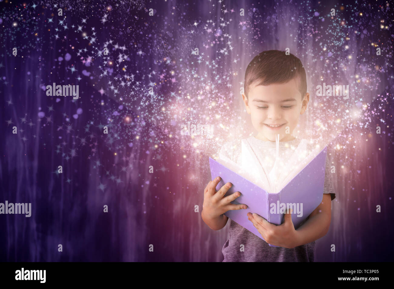 Cute little boy reading magic book on dark color background Stock Photo ...