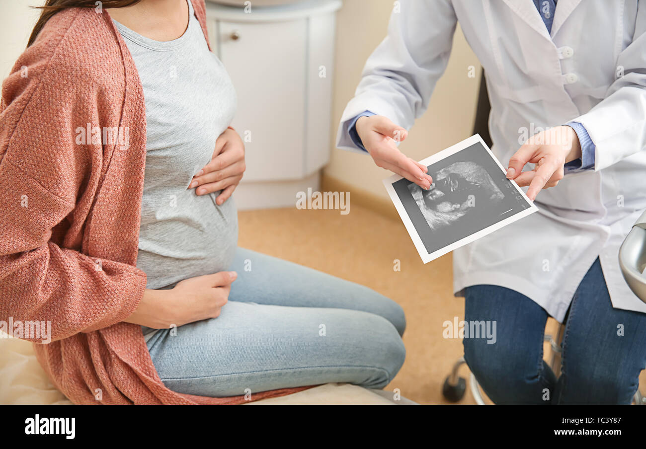 Female ultrasonographer working with pregnant woman in modern clinic ...