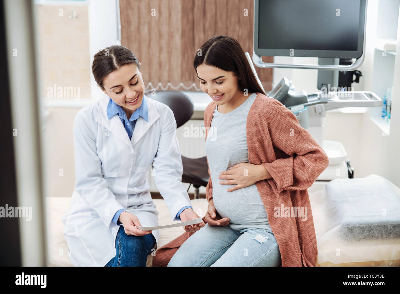 Female ultrasonographer working with pregnant woman in modern clinic ...