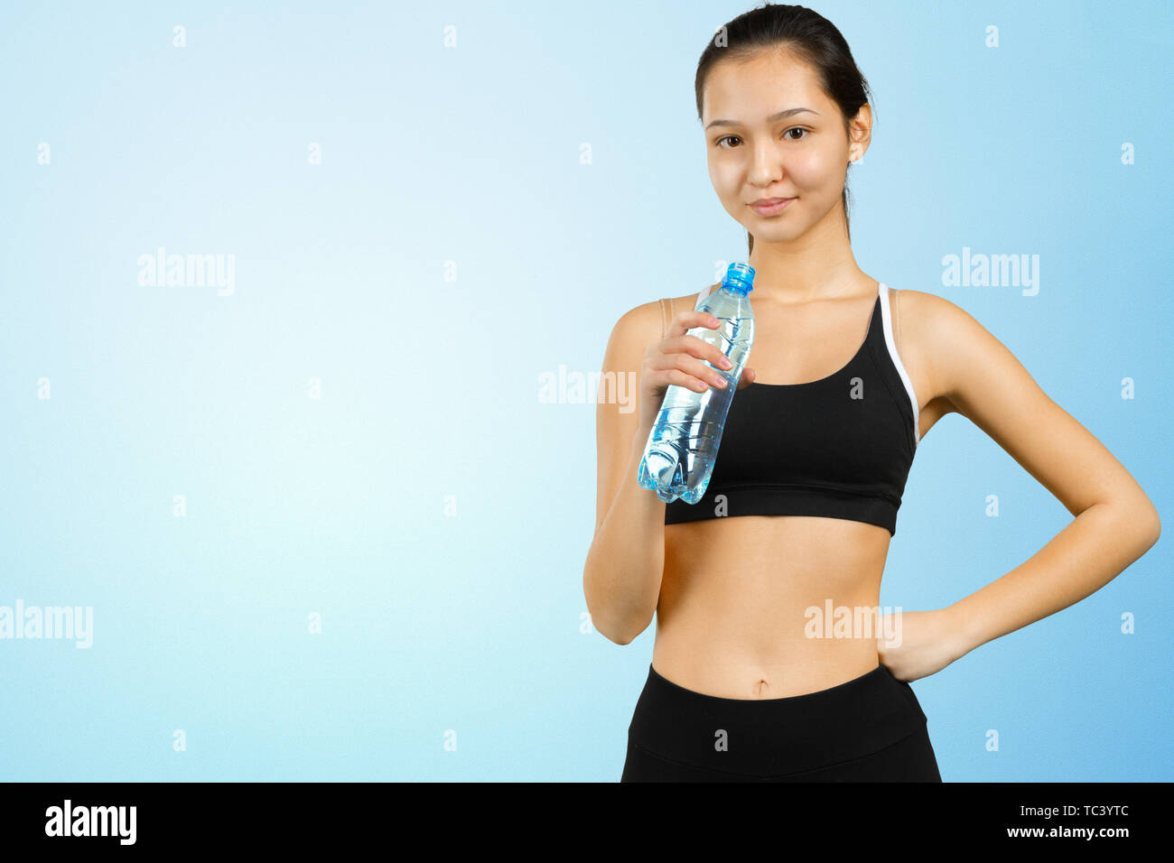 Beautiful young fitness woman with perfect body shape drinking fresh ...