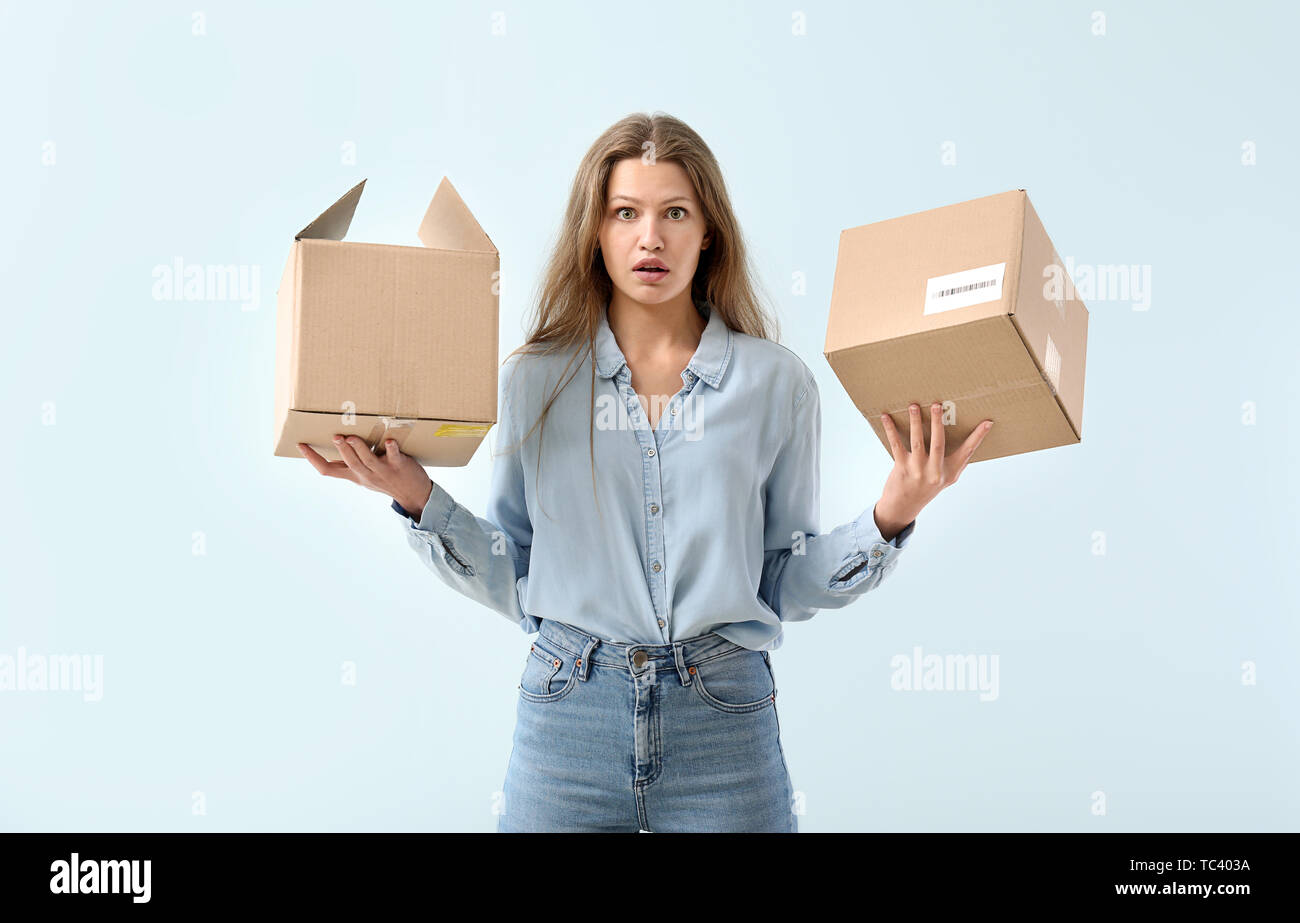 Shocked woman with cardboard boxes on light background Stock Photo - Alamy