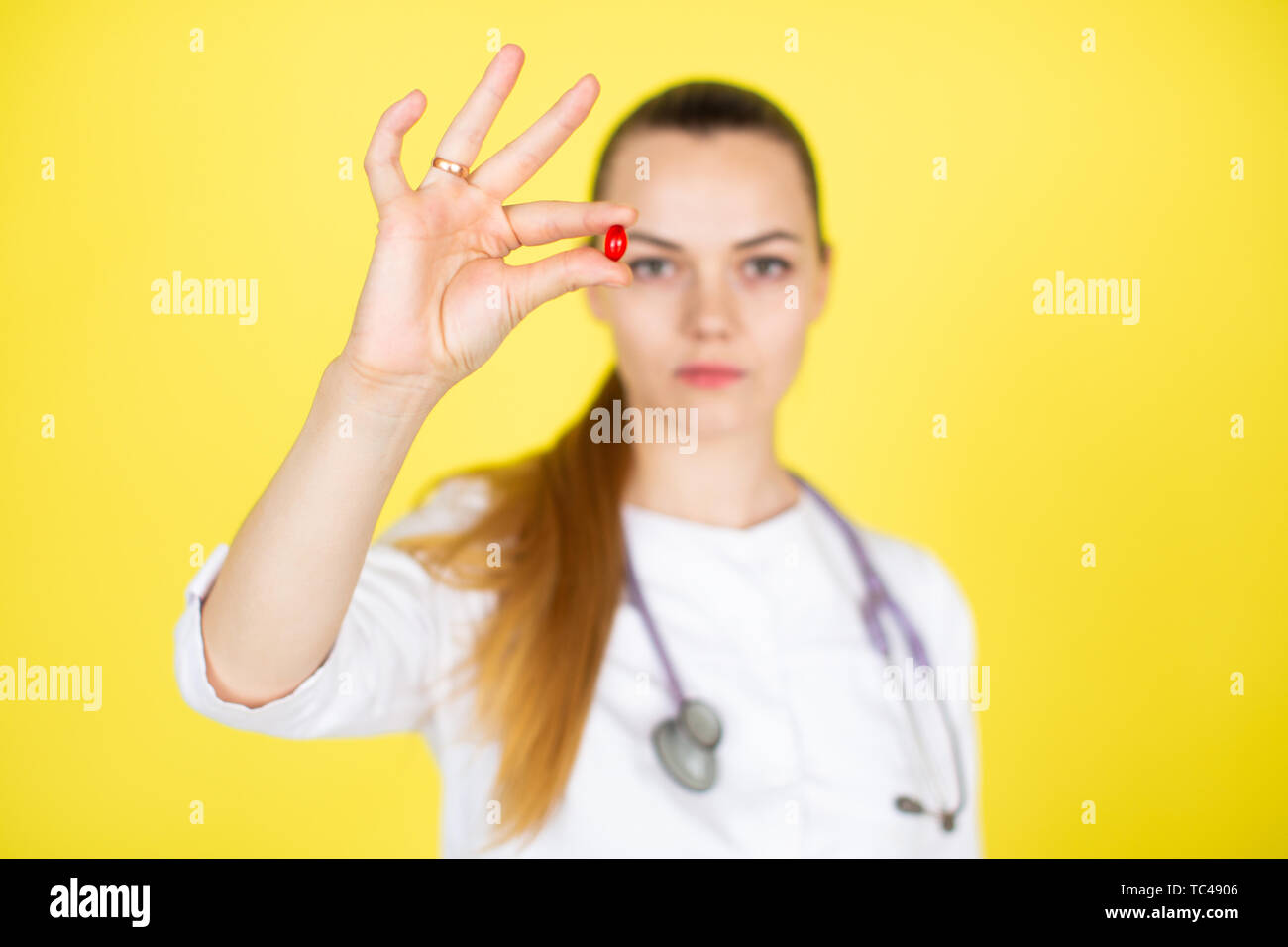 Young attractive blonde female doctor holds red pill in her hand ...