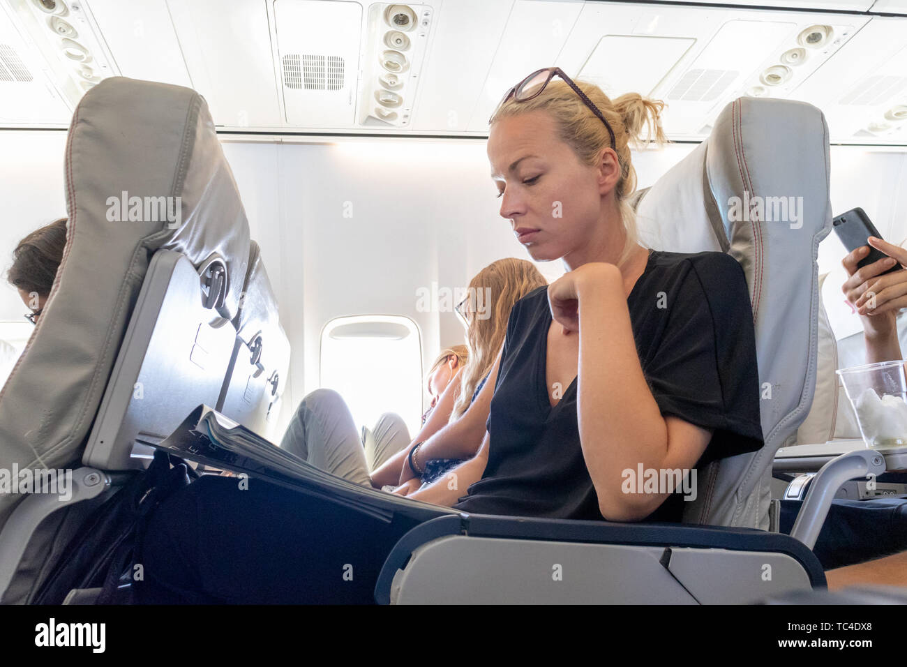 Woman reading magazine on airplane during flight. Female traveler ...