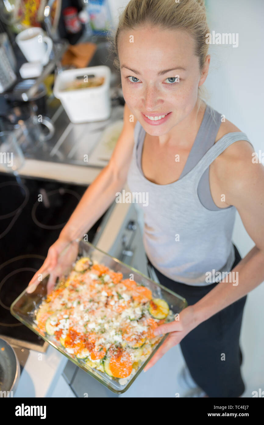 Smiling young healthy woman holding and proudly showing glass baking ...