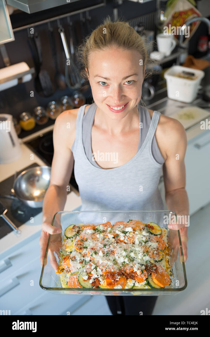 Smiling young healthy woman holding and proudly showing glass baking ...