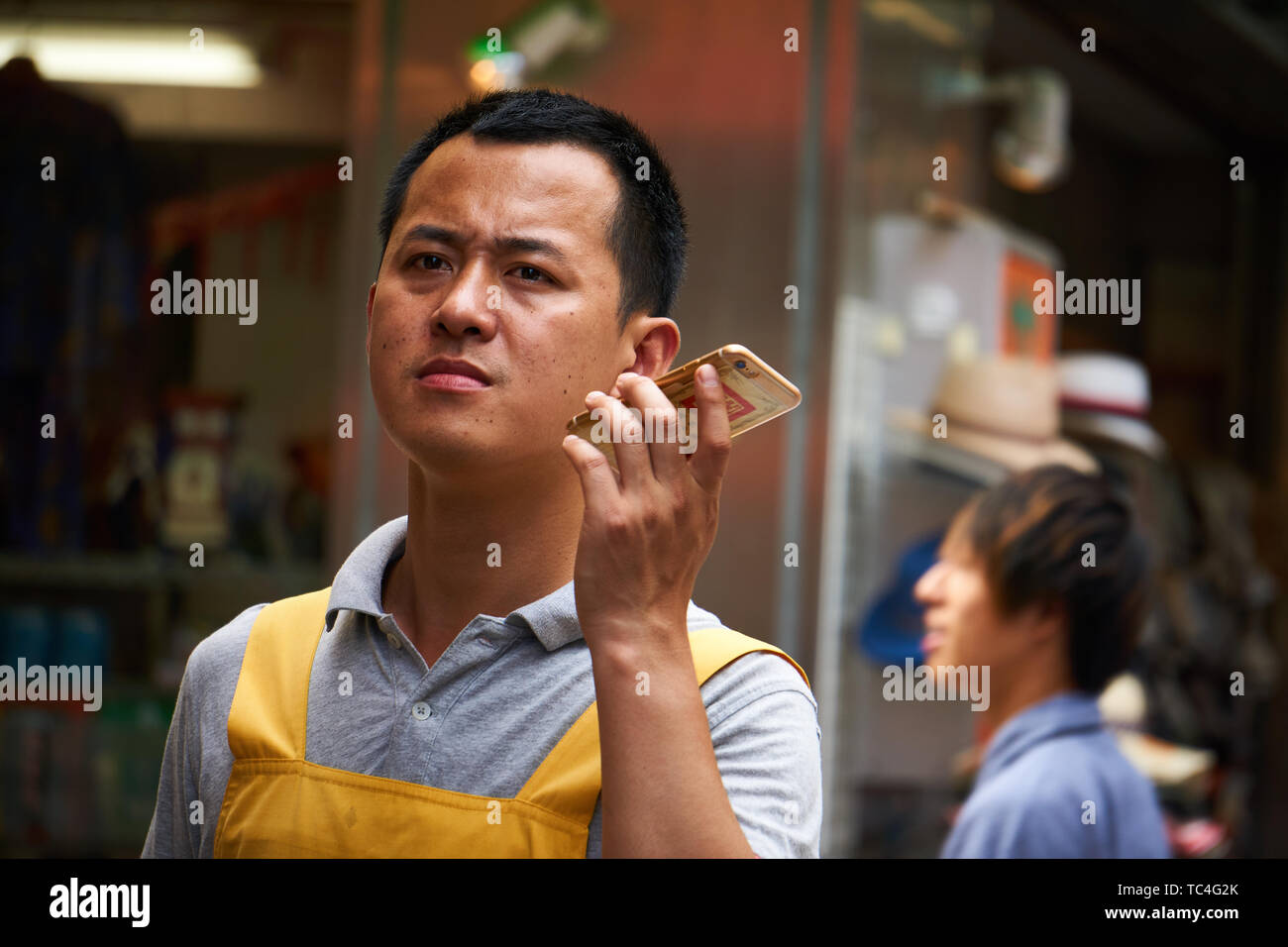 Chinese man stares while holding smartphone (mobile, cell phone) in ...