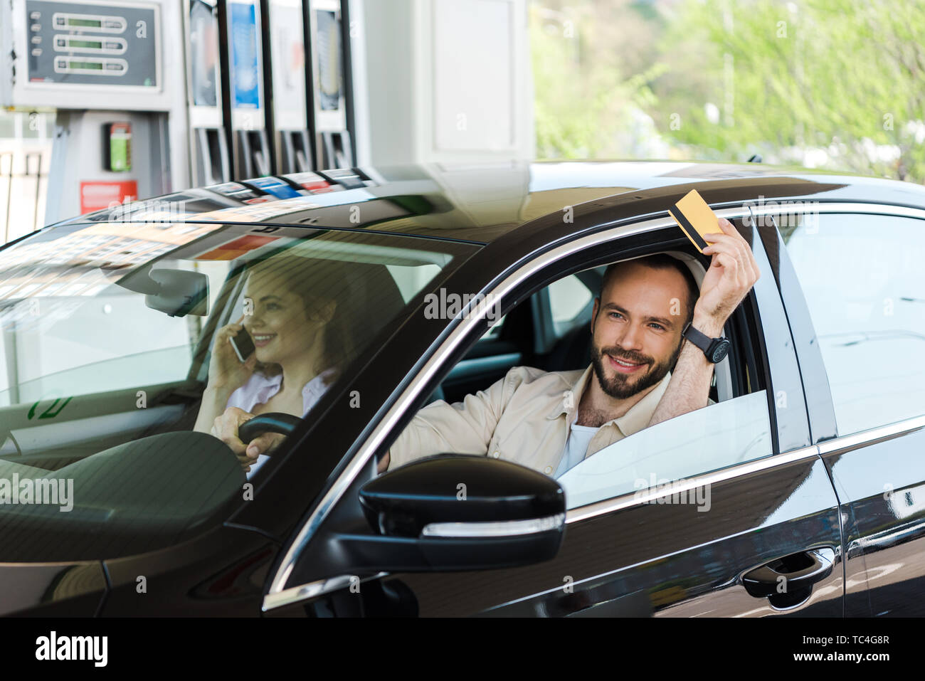 happy man holding credit card while driving car at gas station Stock ...