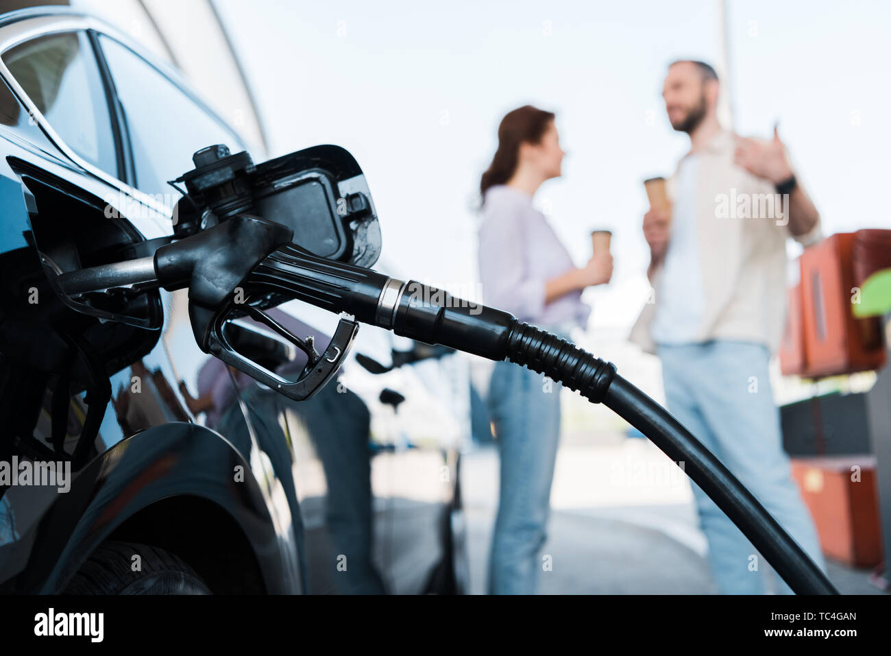 selective focus of black automobile refueling with benzine near man and ...